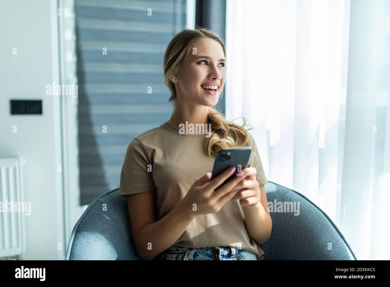 Beautiful woman sitting on a chair and texting a phone message Stock ...