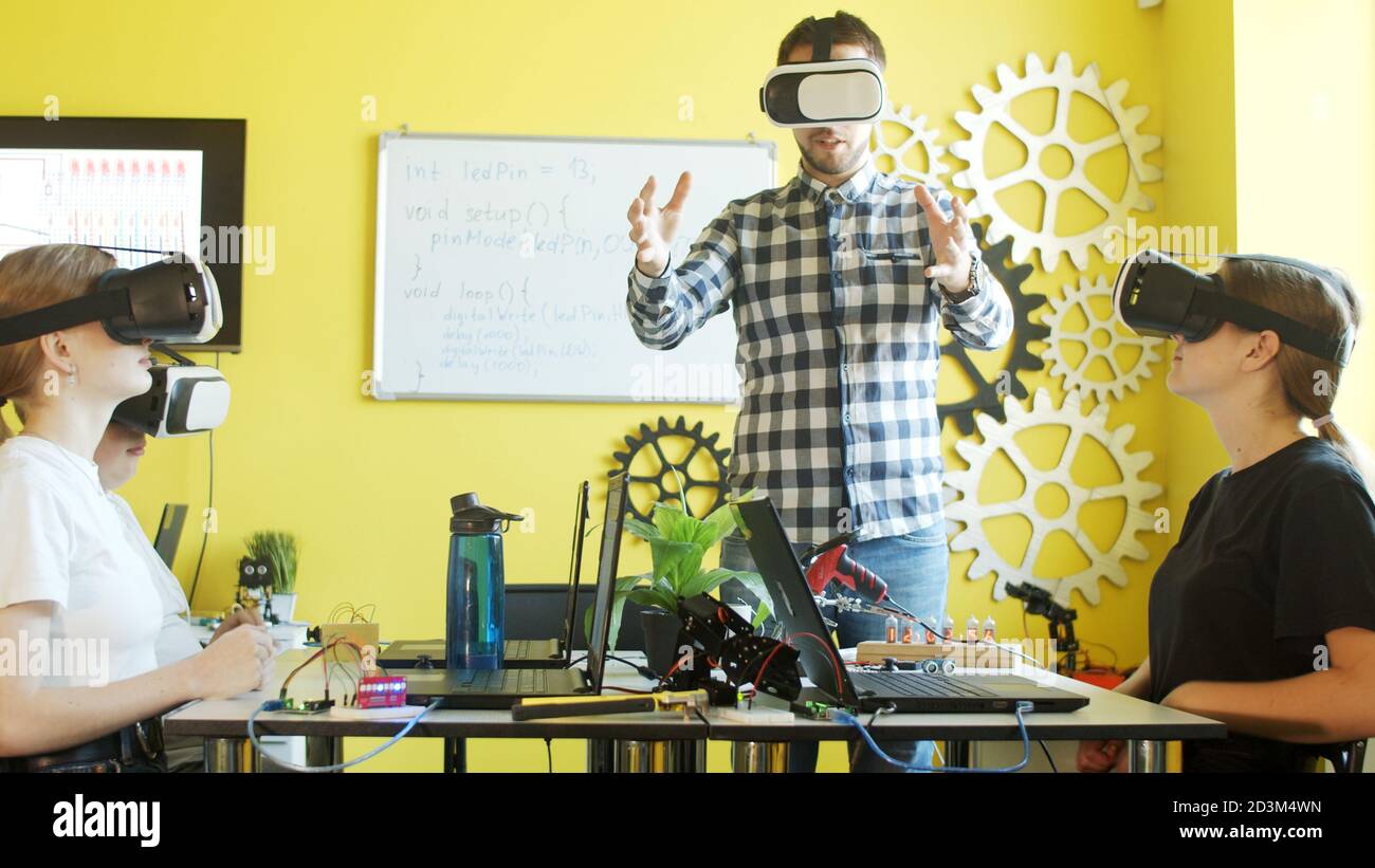 Young students and teacher with robot in classroom Stock Photo - Alamy