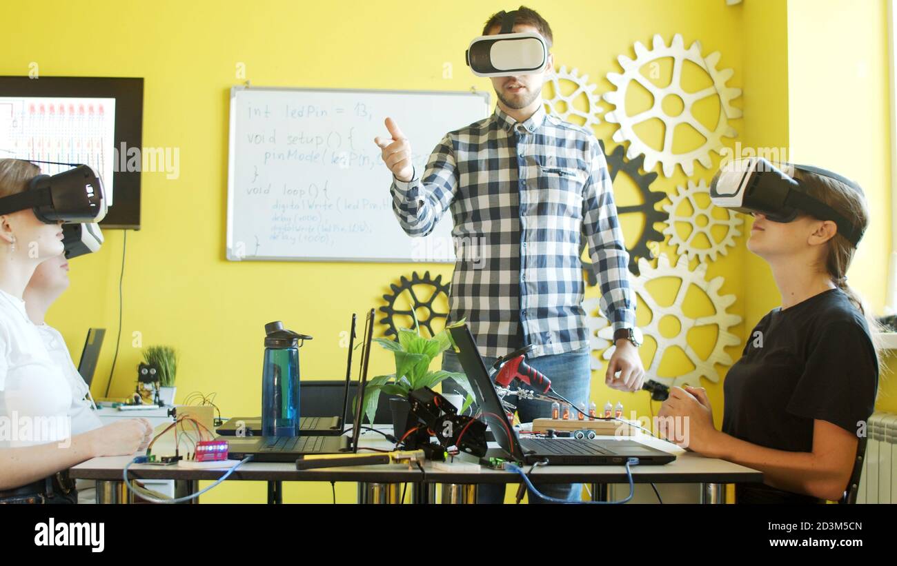 Young students and teacher with robot in classroom Stock Photo - Alamy
