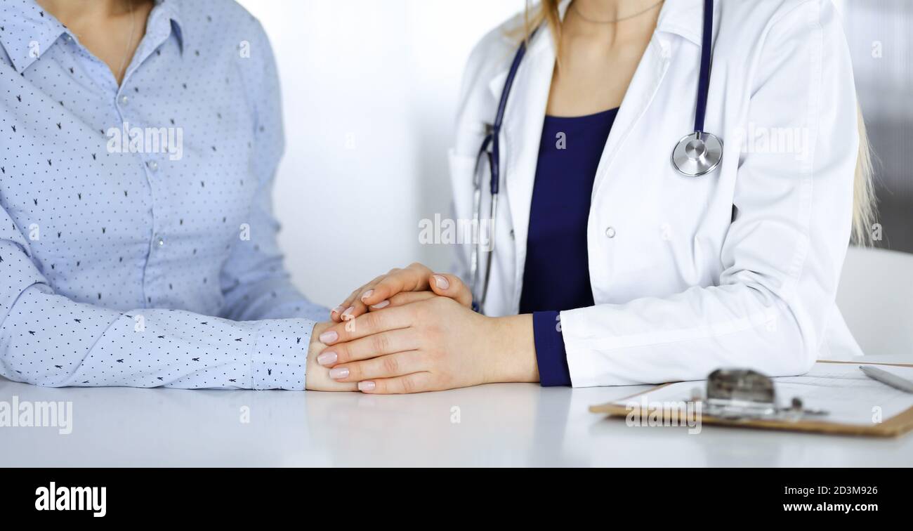 Unknown woman-doctor is holding her patient's hands to reassure a ...
