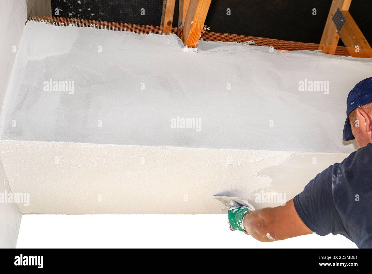 A construction worker applies and blurs a white layer of silicone ...