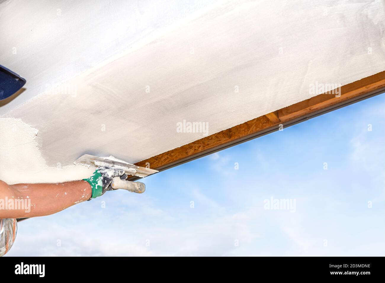 A construction worker applies and blurs a white layer of silicone ...