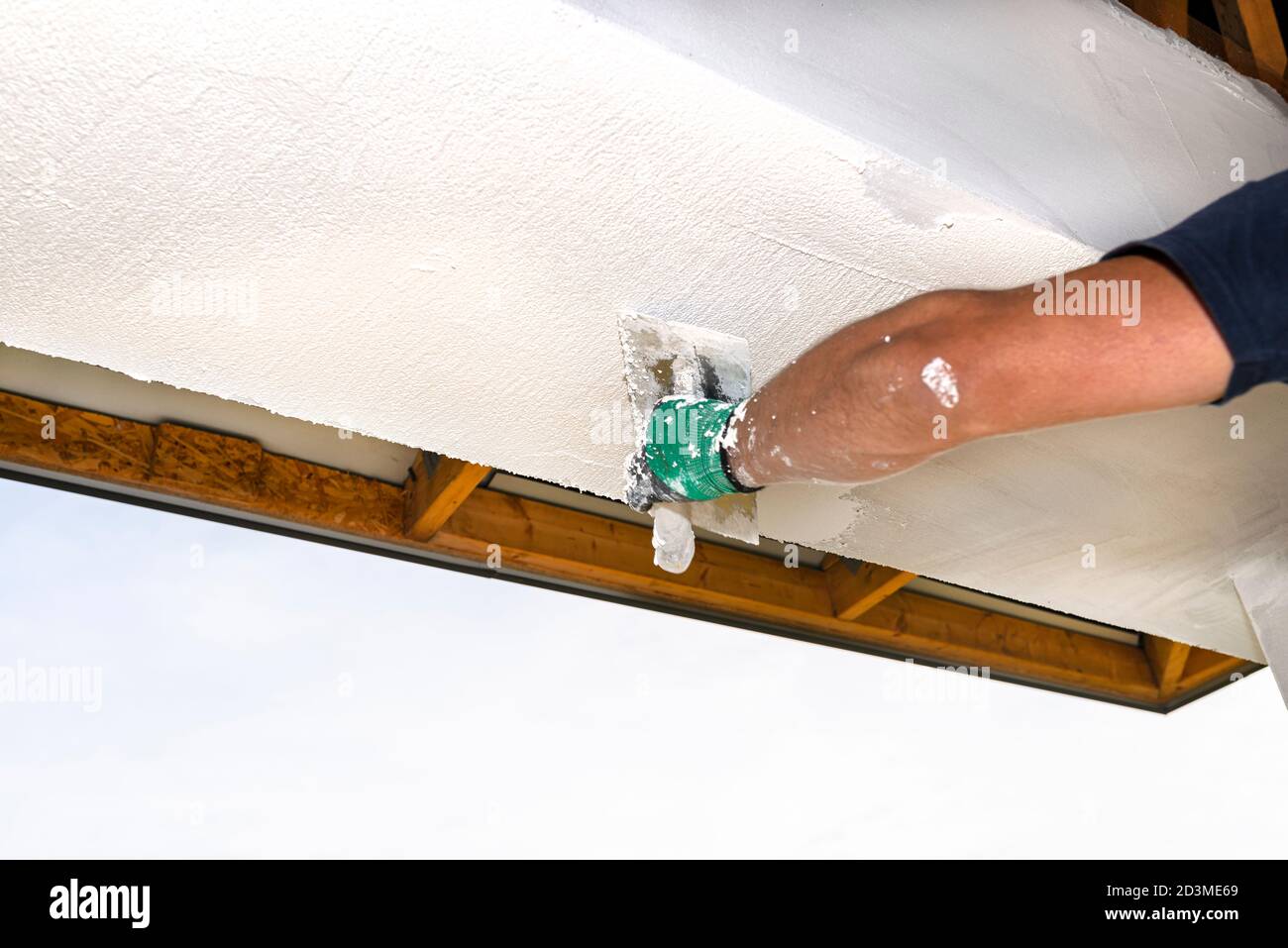 A construction worker applies and blurs a white layer of silicone ...