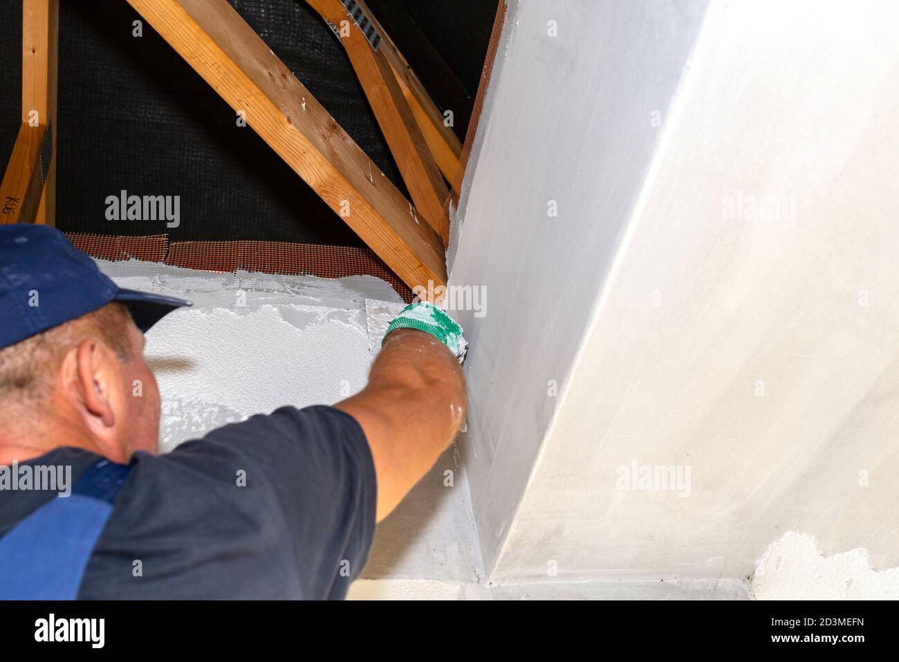 A construction worker applies and blurs a white layer of silicone ...