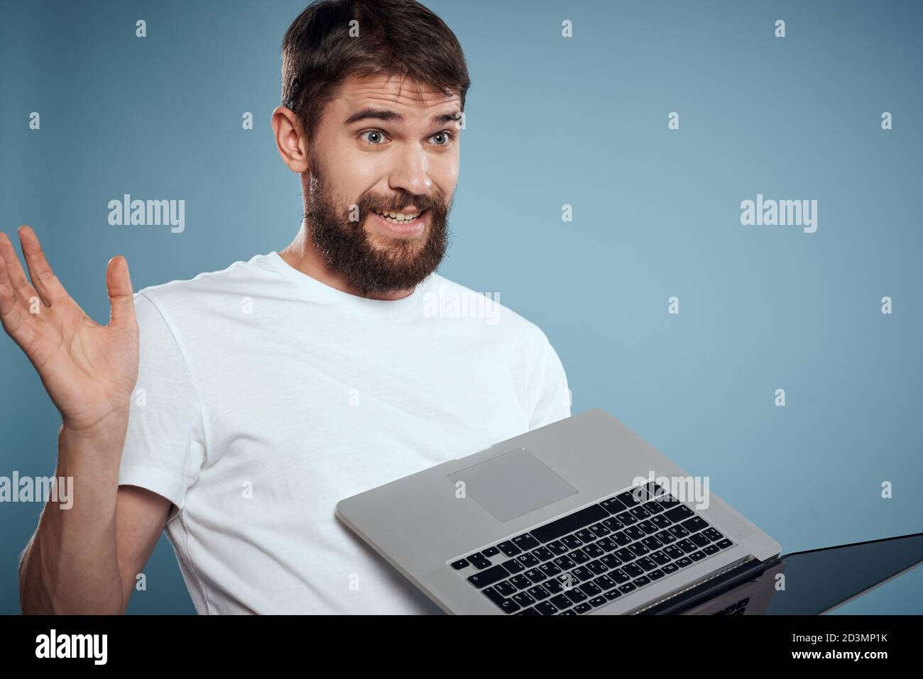 Emotional man with laptop in hands on blue background monitor keyboard ...
