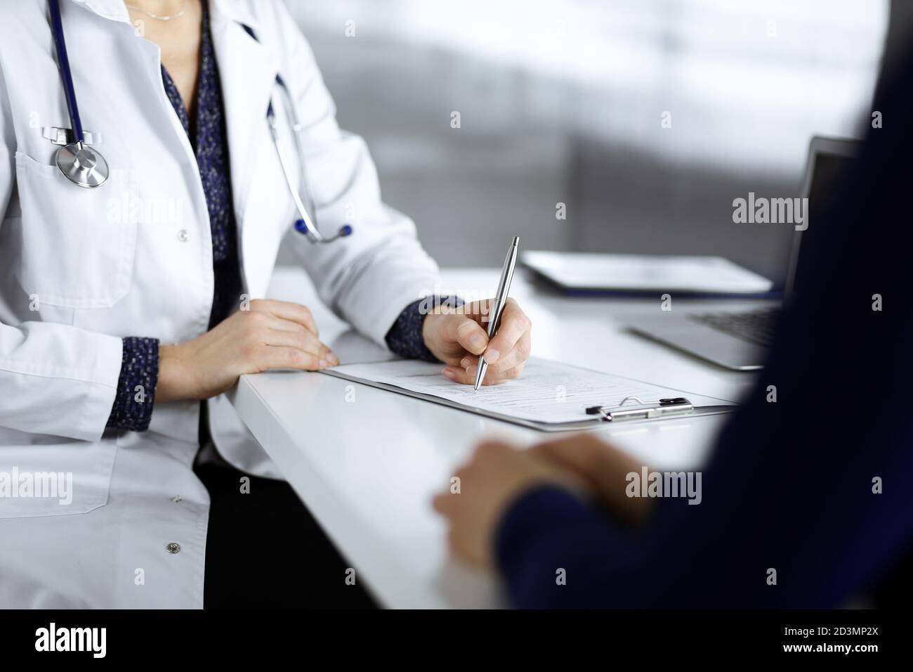 Unknown woman-doctor is writing some medical recommendations to her ...