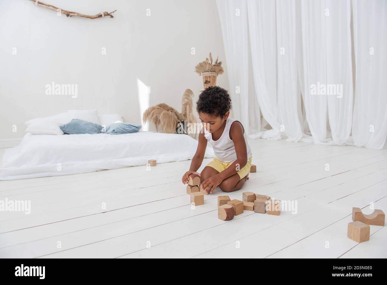 Little happy boy African American play houses with wooden eco bricks ...