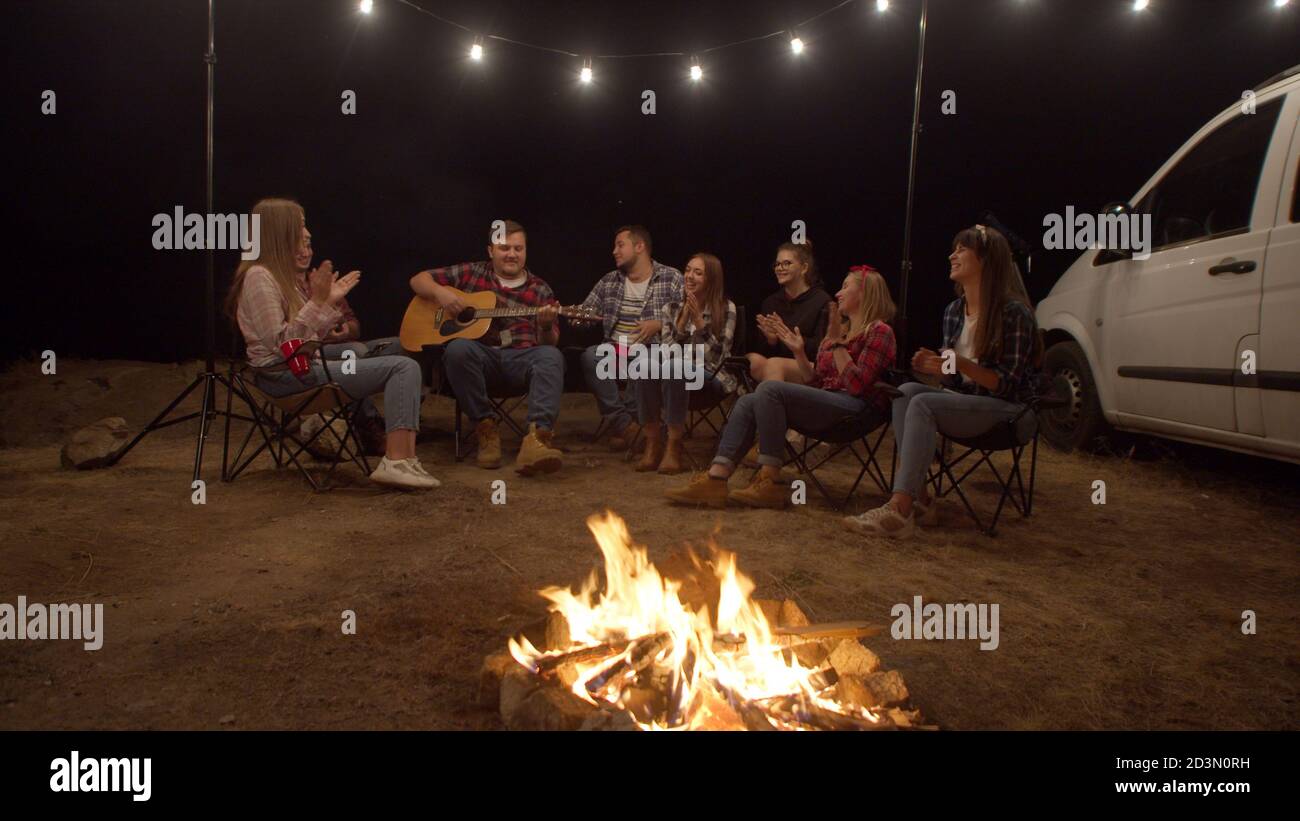 Young people chilling around campfire in evening Stock Photo - Alamy