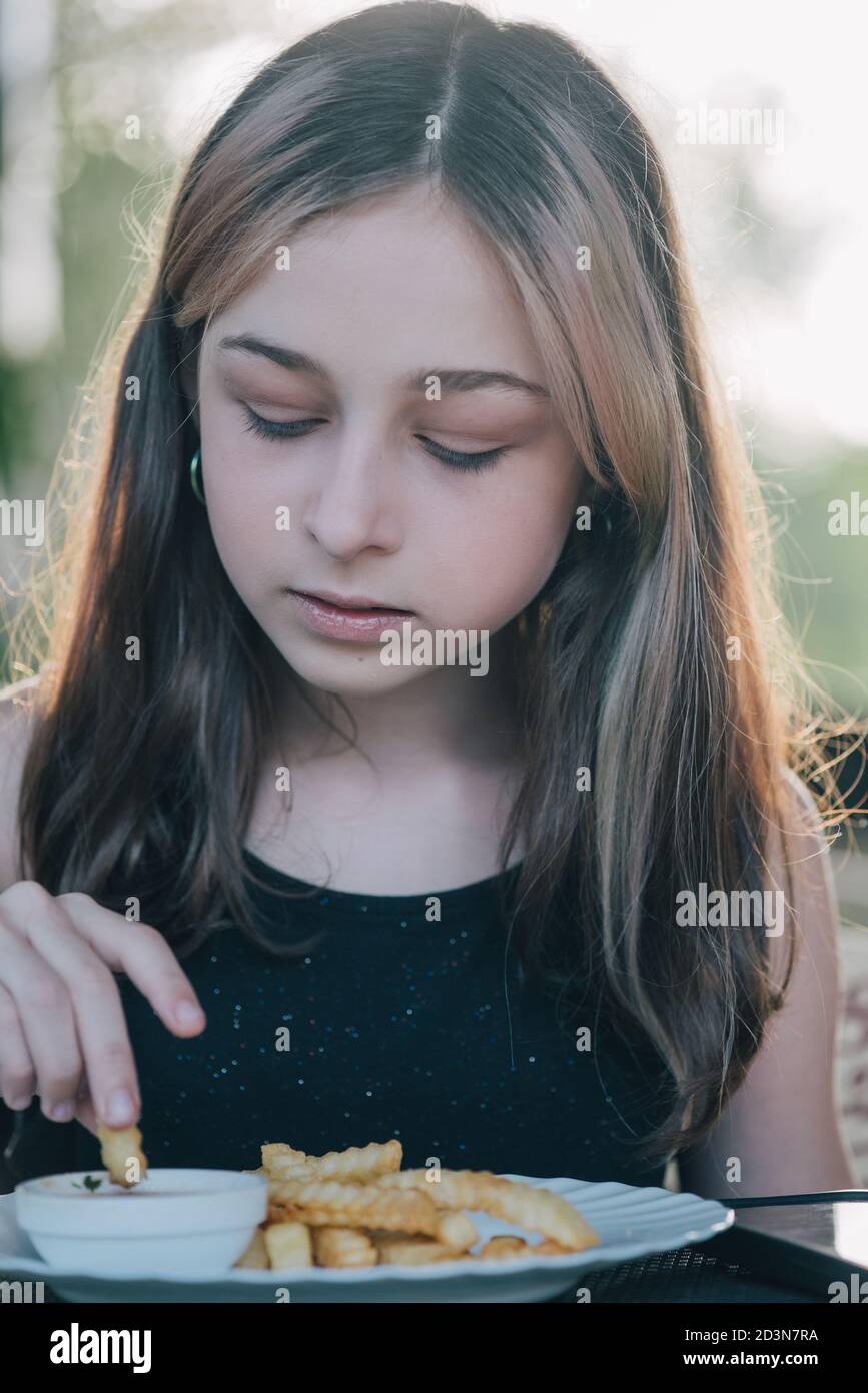 happy little girl eating a french fries. Beautifullittle girl sitting ...