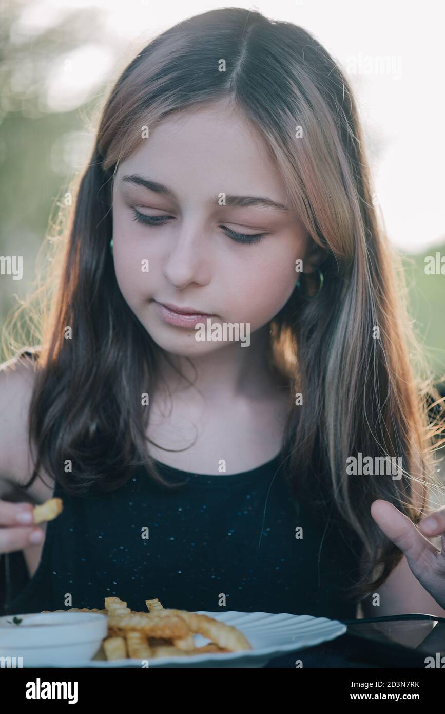 happy little girl eating a french fries. Beautifullittle girl sitting ...