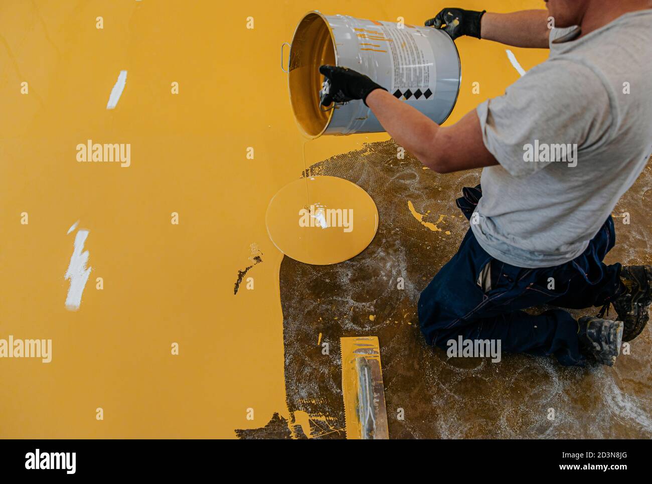 Worker, coating floor with self-leveling epoxy resin in industrial ...