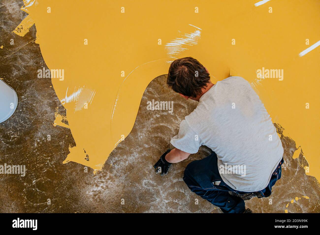 Worker, coating floor with self-leveling epoxy resin in industrial ...