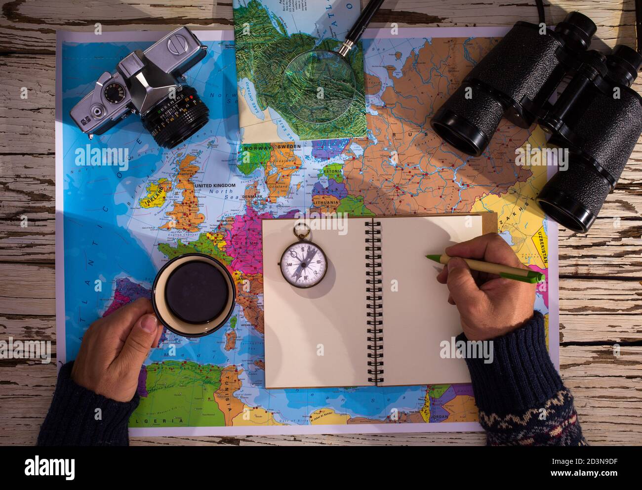 Flat lay of the travel planning concept. Top view of man hands wriìting on a diary, on the table ...