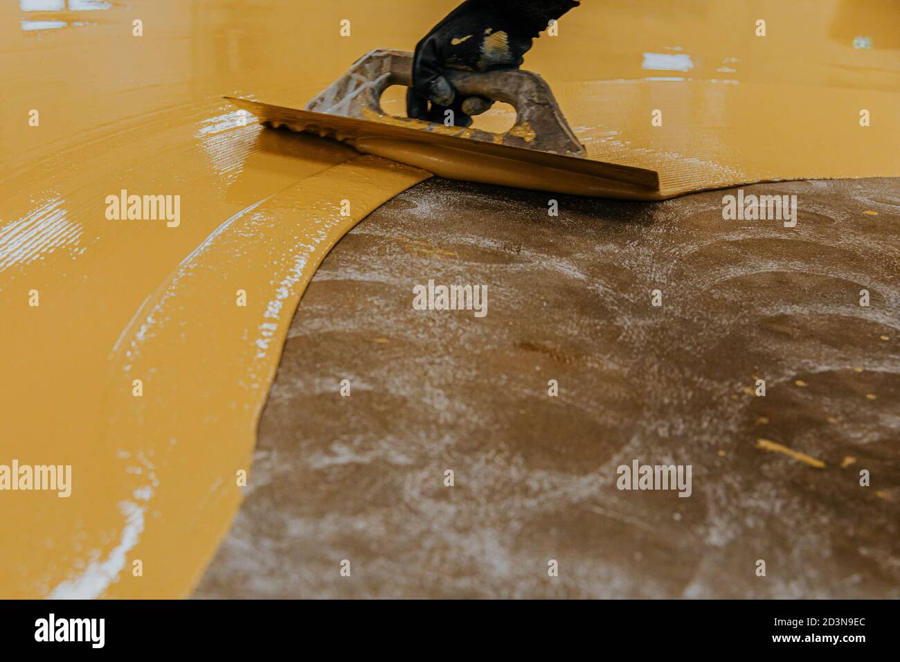 Worker, coating floor with self-leveling epoxy resin in industrial ...
