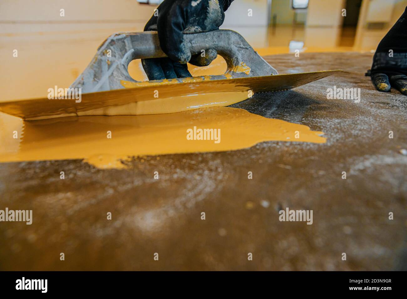 Worker, coating floor with self-leveling epoxy resin in industrial ...
