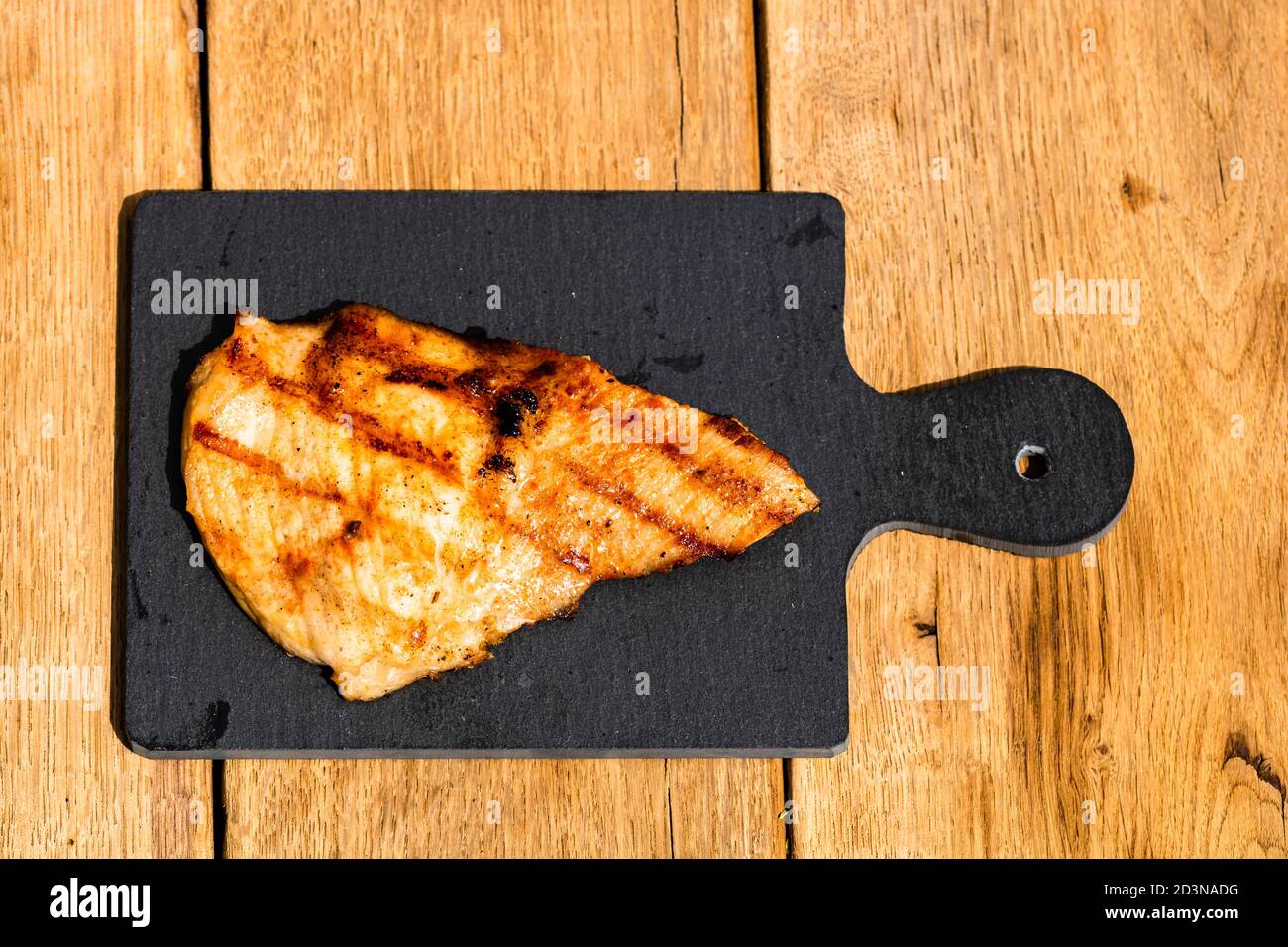 Close up of grilled steak on small black chopping board isolated ...