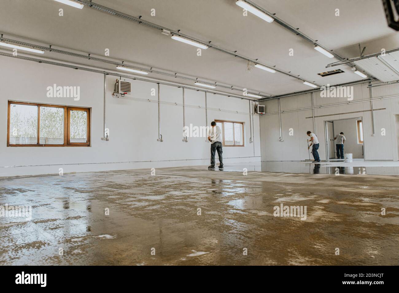 Construction workers apply epoxy resin in an industrial hall Stock ...