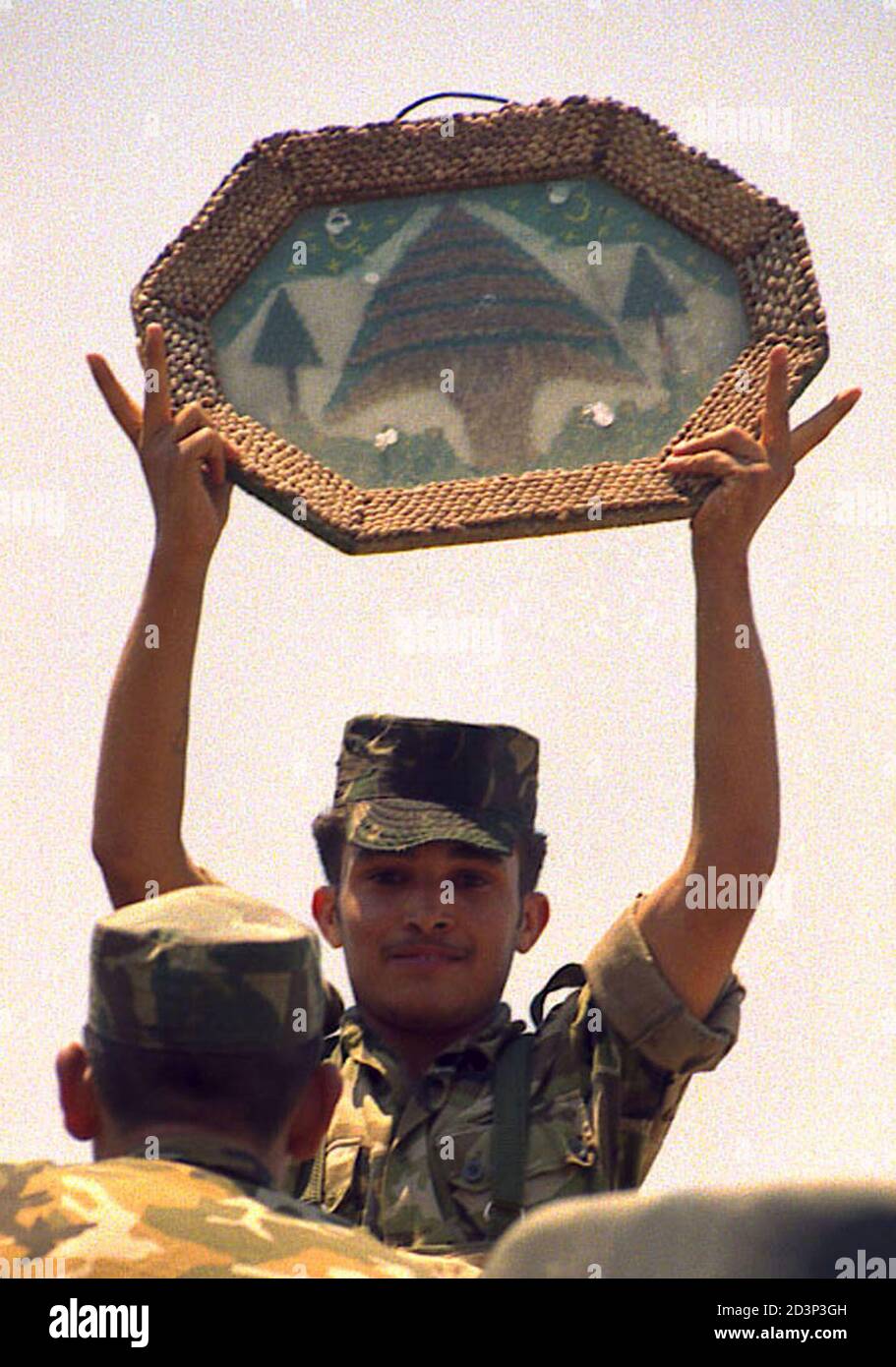 A Syrian soldier atop a truck, holds up a hand made picture of a cedar ...