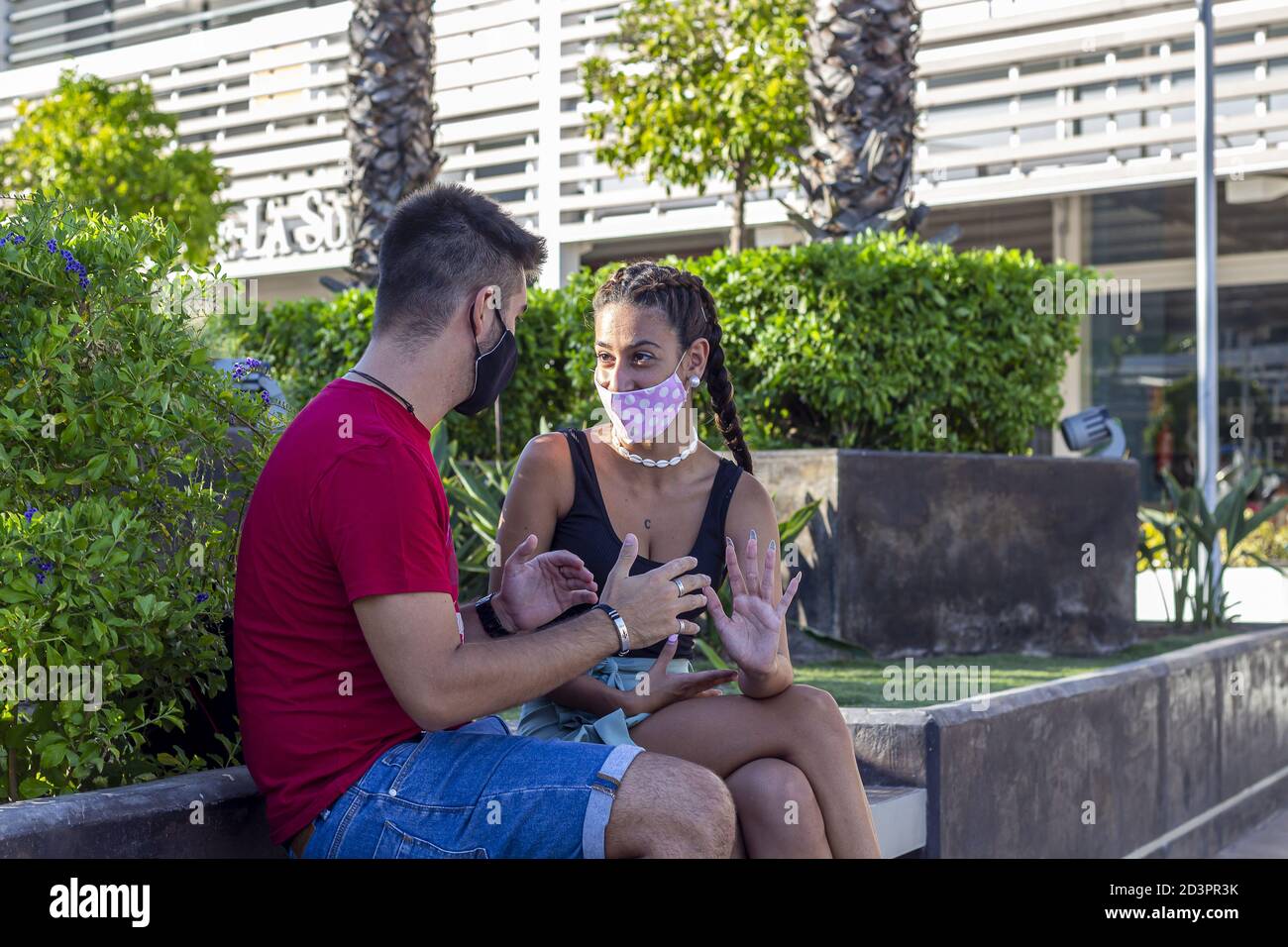 Young couple with a medical mask talking with each other in the park ...