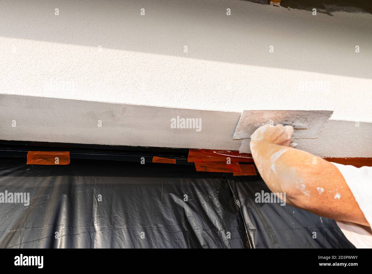 A construction worker applies and blurs a white layer of silicone ...