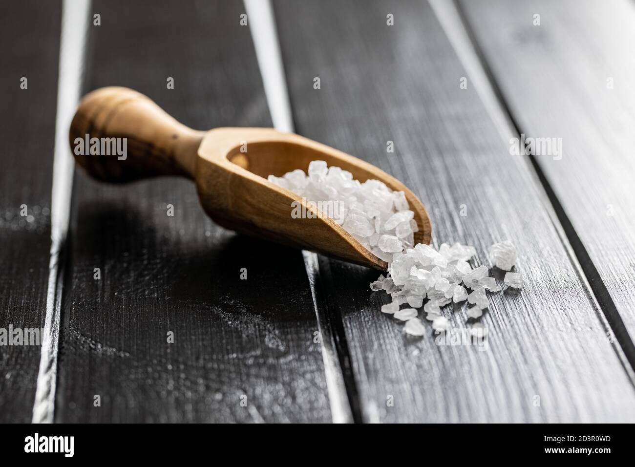 White coarse salt in wooden scoop on black table Stock Photo - Alamy