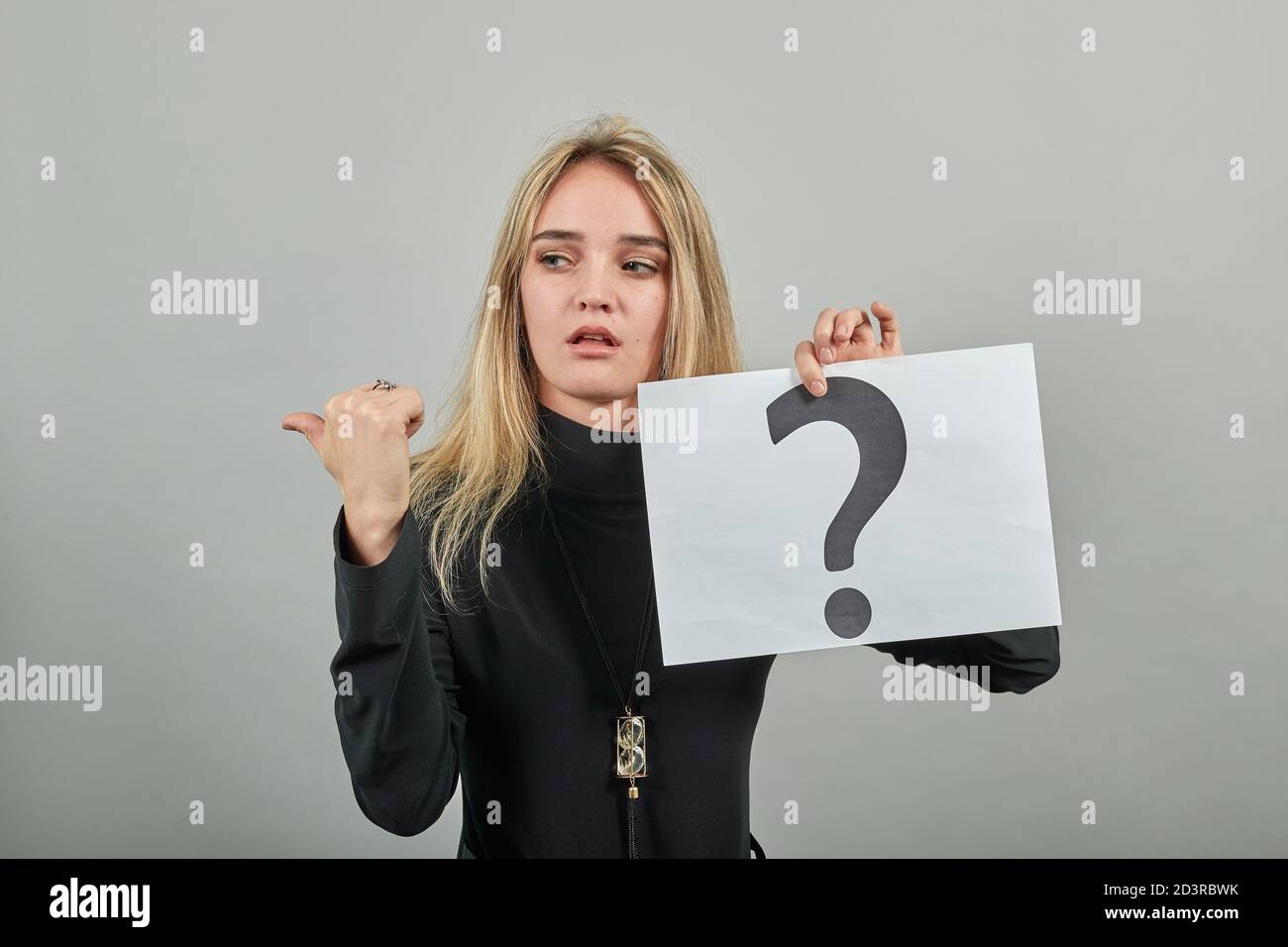 Black question mark on a piece of white paper. Close-up hand holding ...