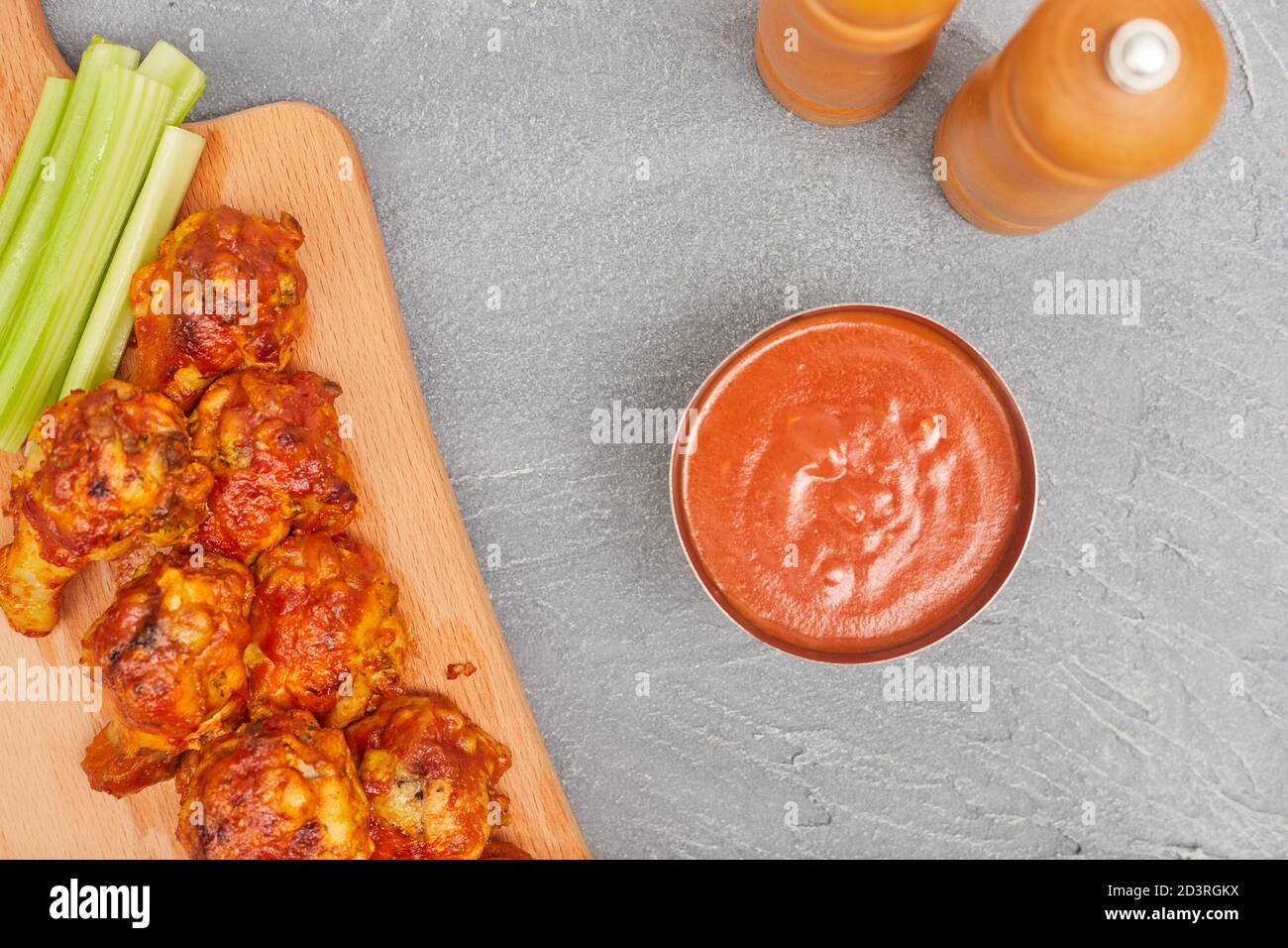 Buffalo chicken wings on a wooden board with celery on a concrete ...