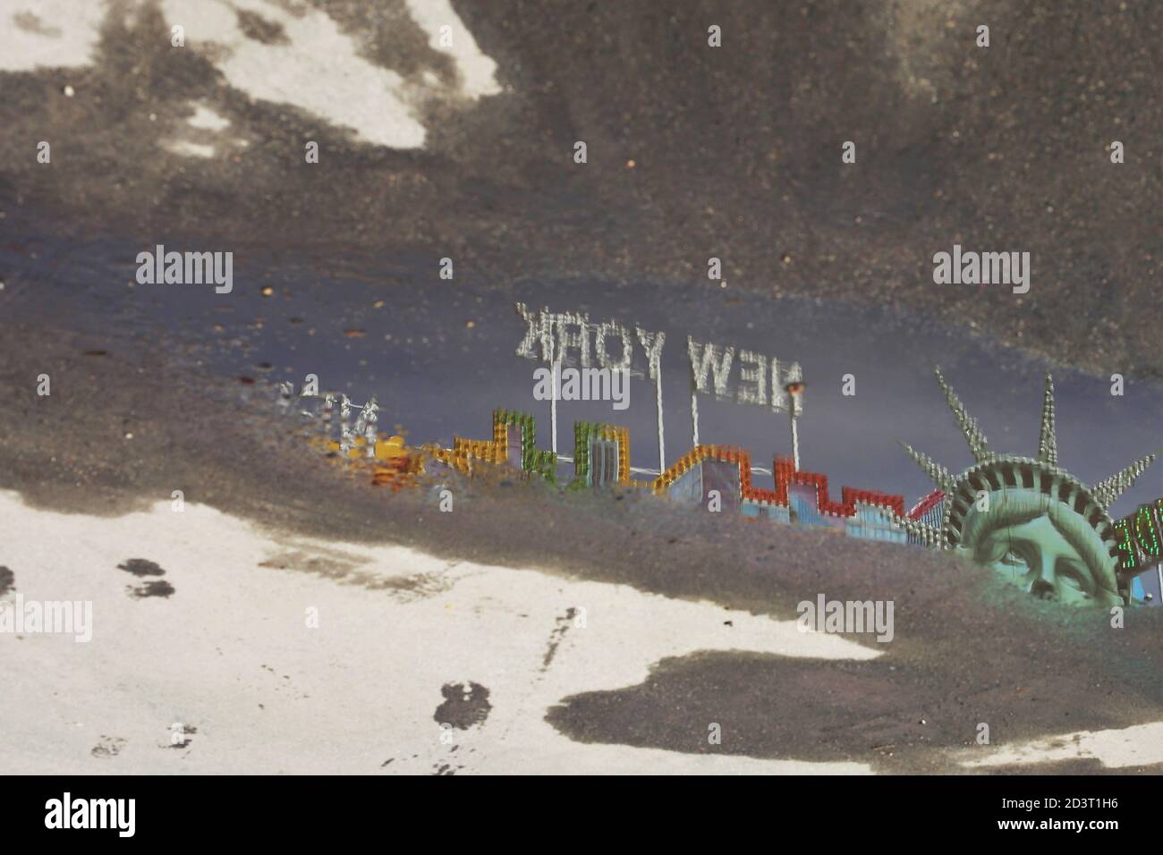 The reflection in a puddle, of a New York carnival ride at the ...