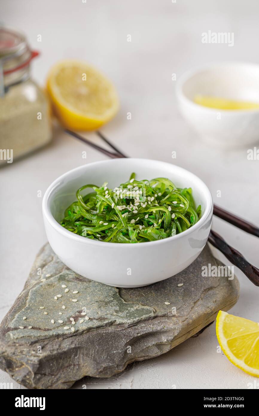Croped photo of green wakame seaweed salad with chopstick and lemon at ...