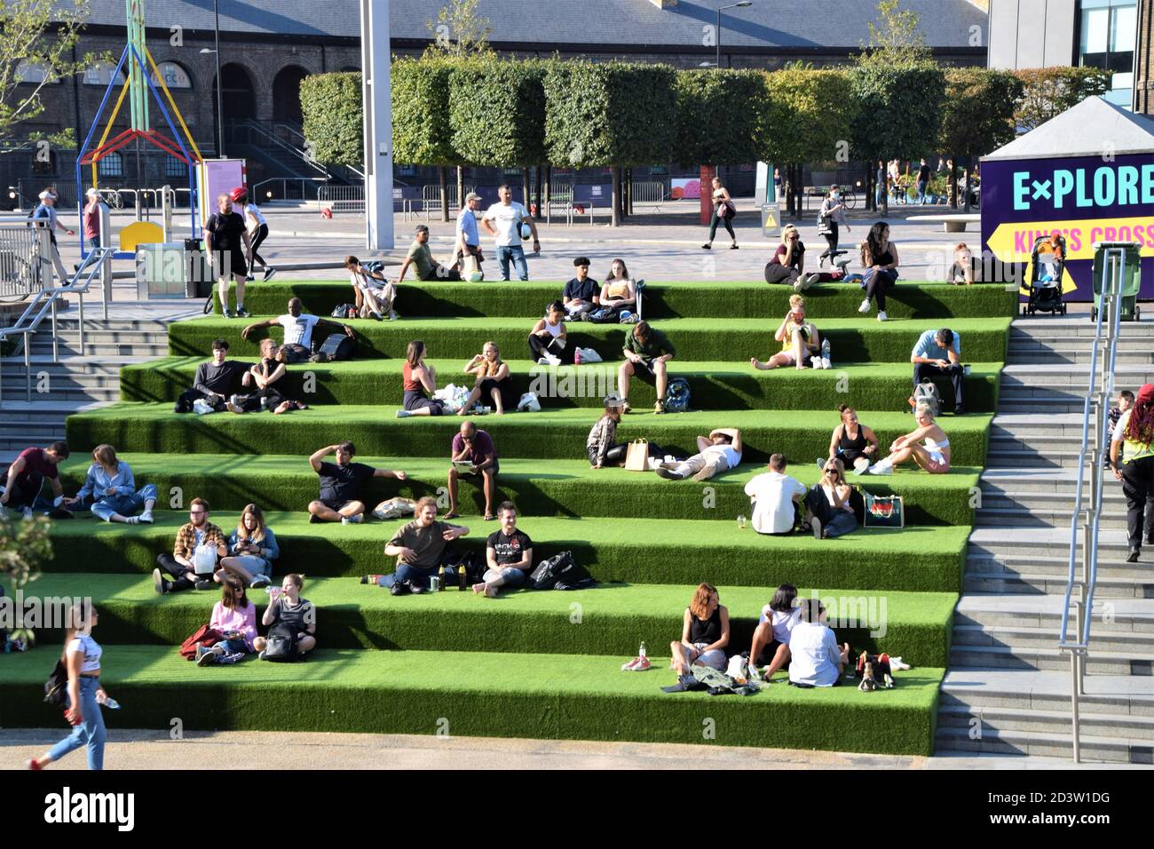 People sitting on the green steps next to Regent's Canal at Granary ...