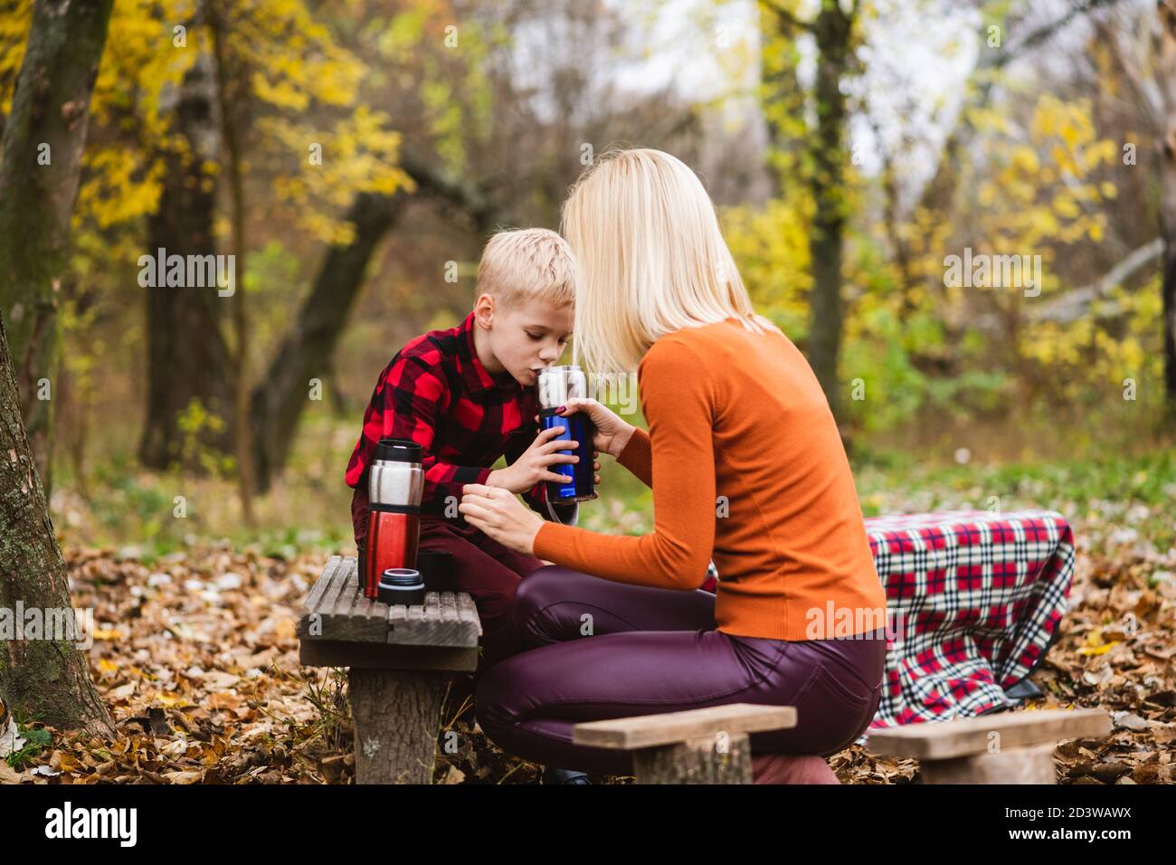 Happy family picnic at picturesque autumn forest. Mom hold stainless ...