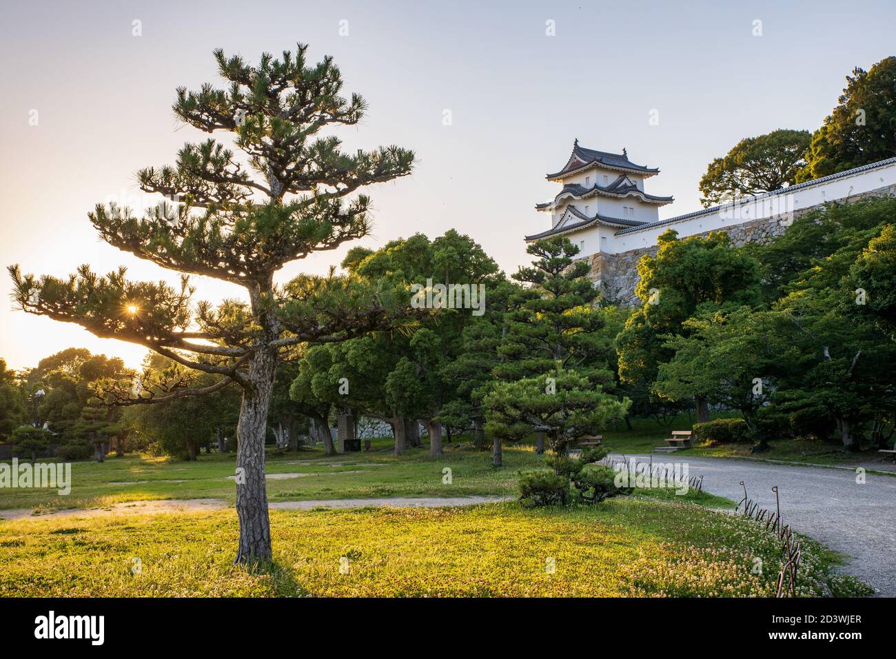 Ancient Japanese castle towers over empty park at sunset Stock Photo ...