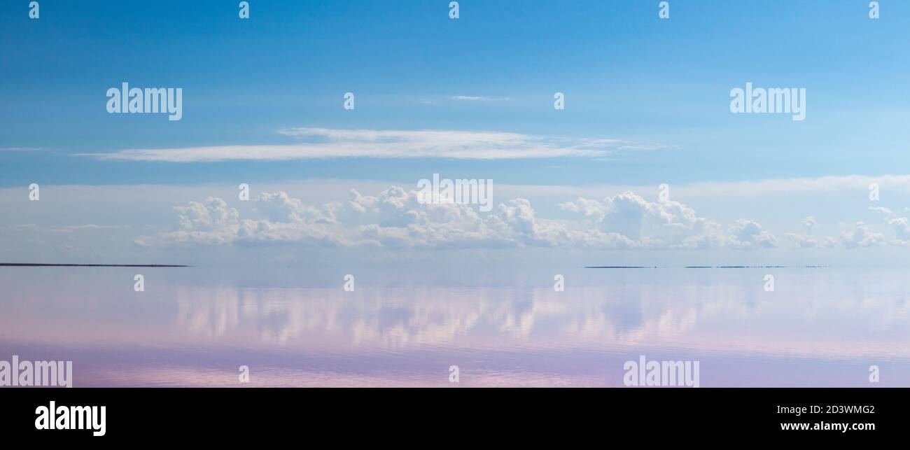 Pink salt lake water surface with mirror reflection of magic clouds ...