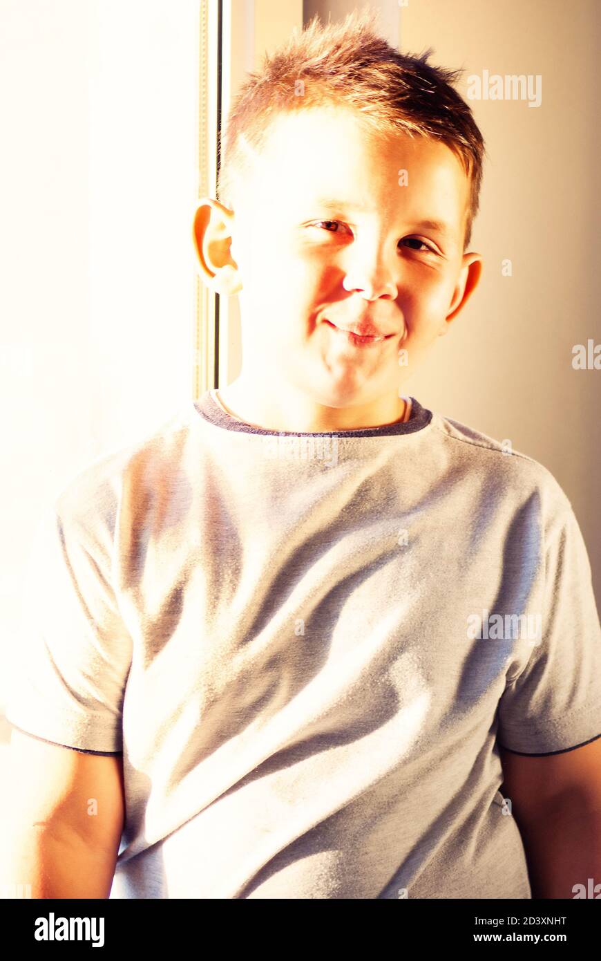 beautiful happy boy posing in front of window at bright light sun beam ...