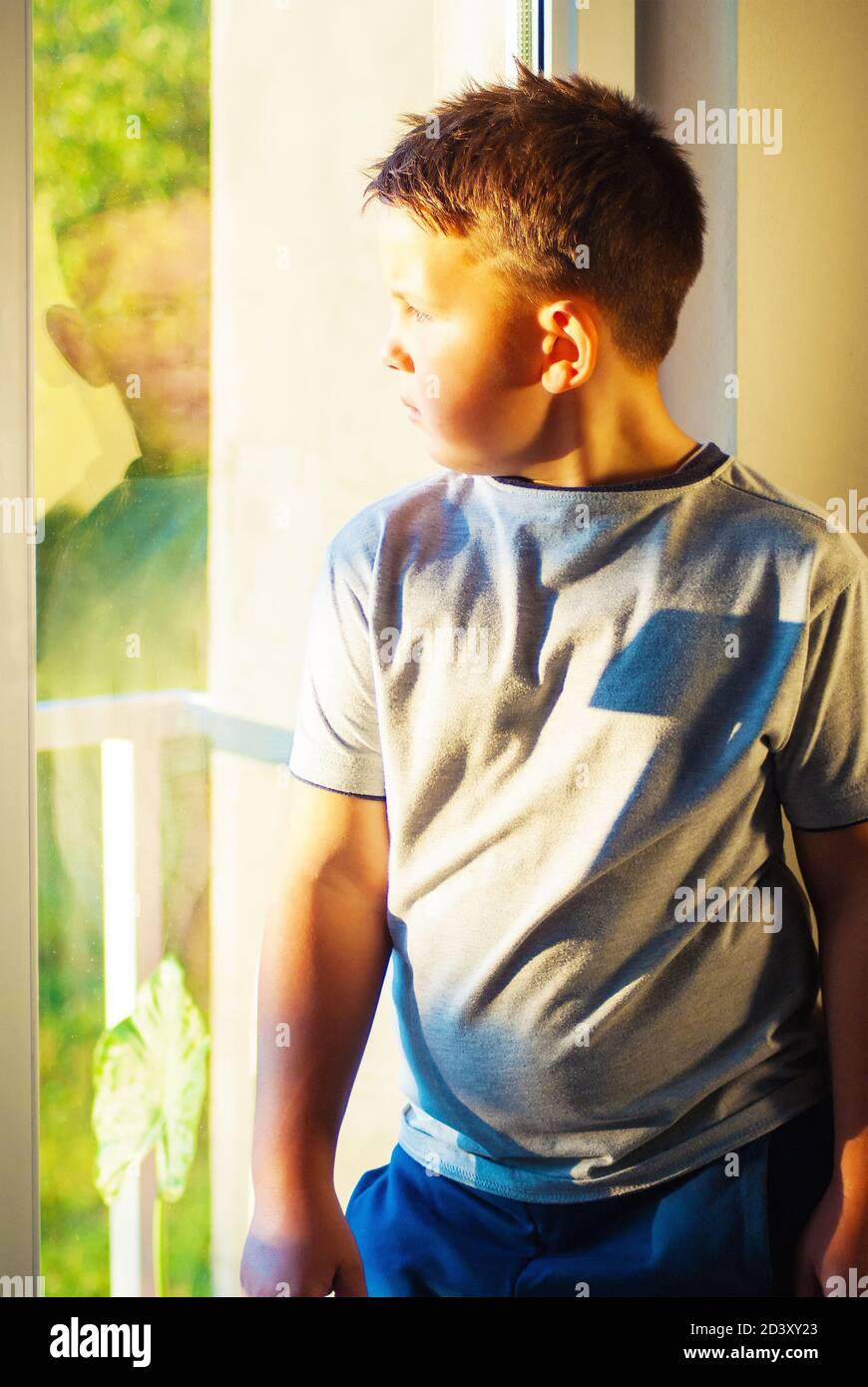 beautiful happy boy posing in front of window at bright light sun beam ...