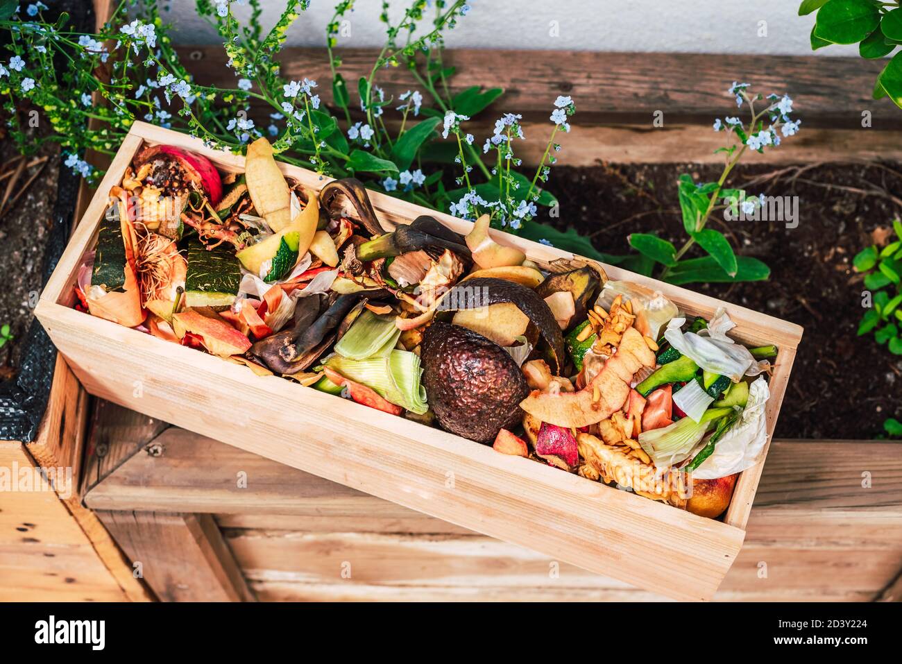 Peelings and organic waste in a wooden crate to create homemade compost ...