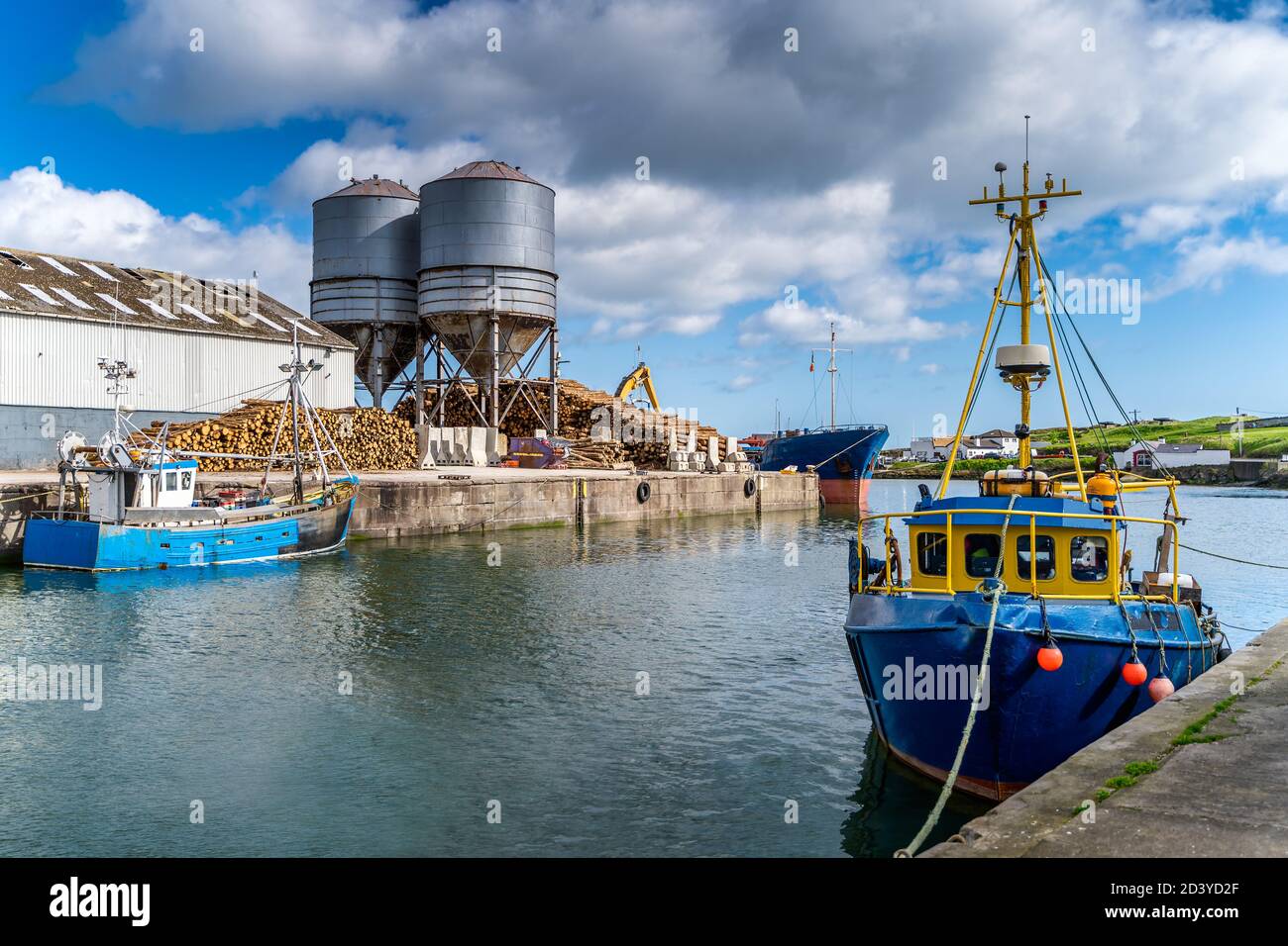 Small fishing boats in Wicklow commercial port with stacks of timber or ...