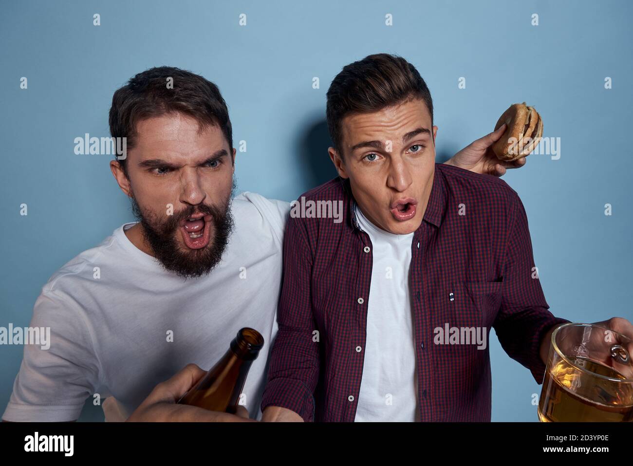 Two cheerful drunk friends drinking beer lifestyle emotions on a blue ...