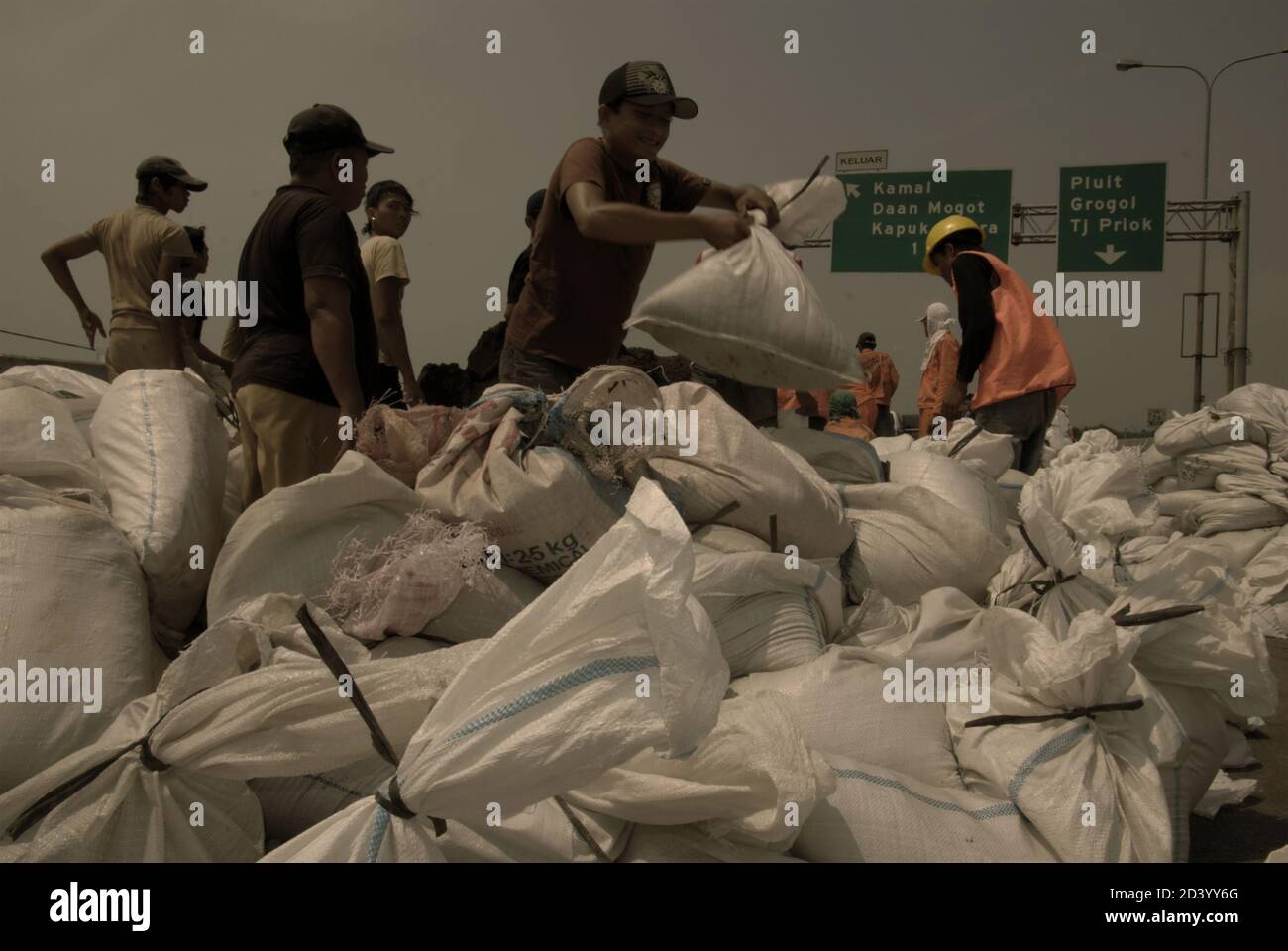 Workers coordinating and moving gunny sacks containing sands to be used ...