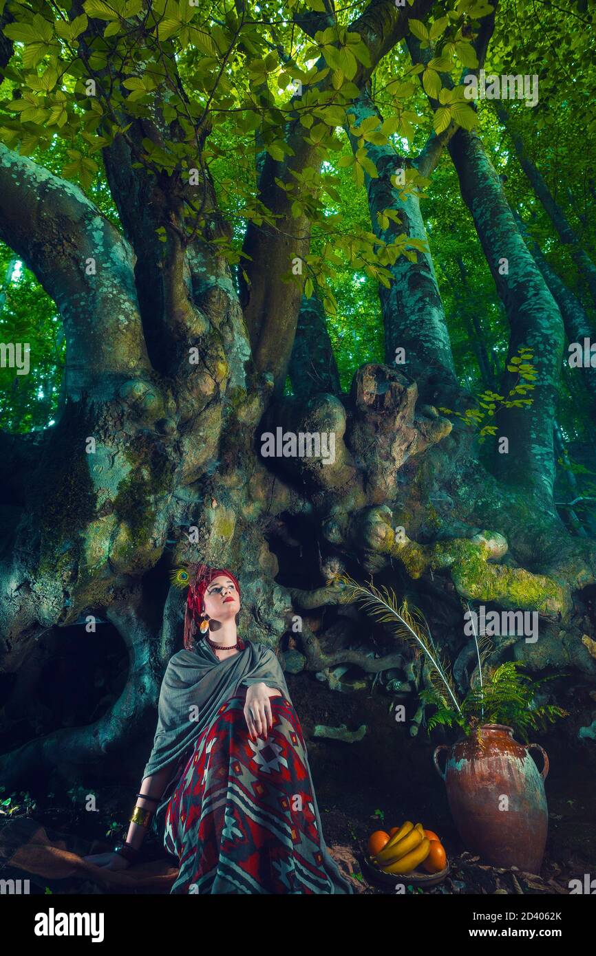 Young woman in traditional clothes sitting under a tree Stock Photo - Alamy