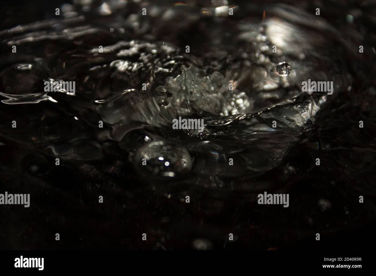 Frozen water spheres slowly falling into a deep liquid swirl with no ...