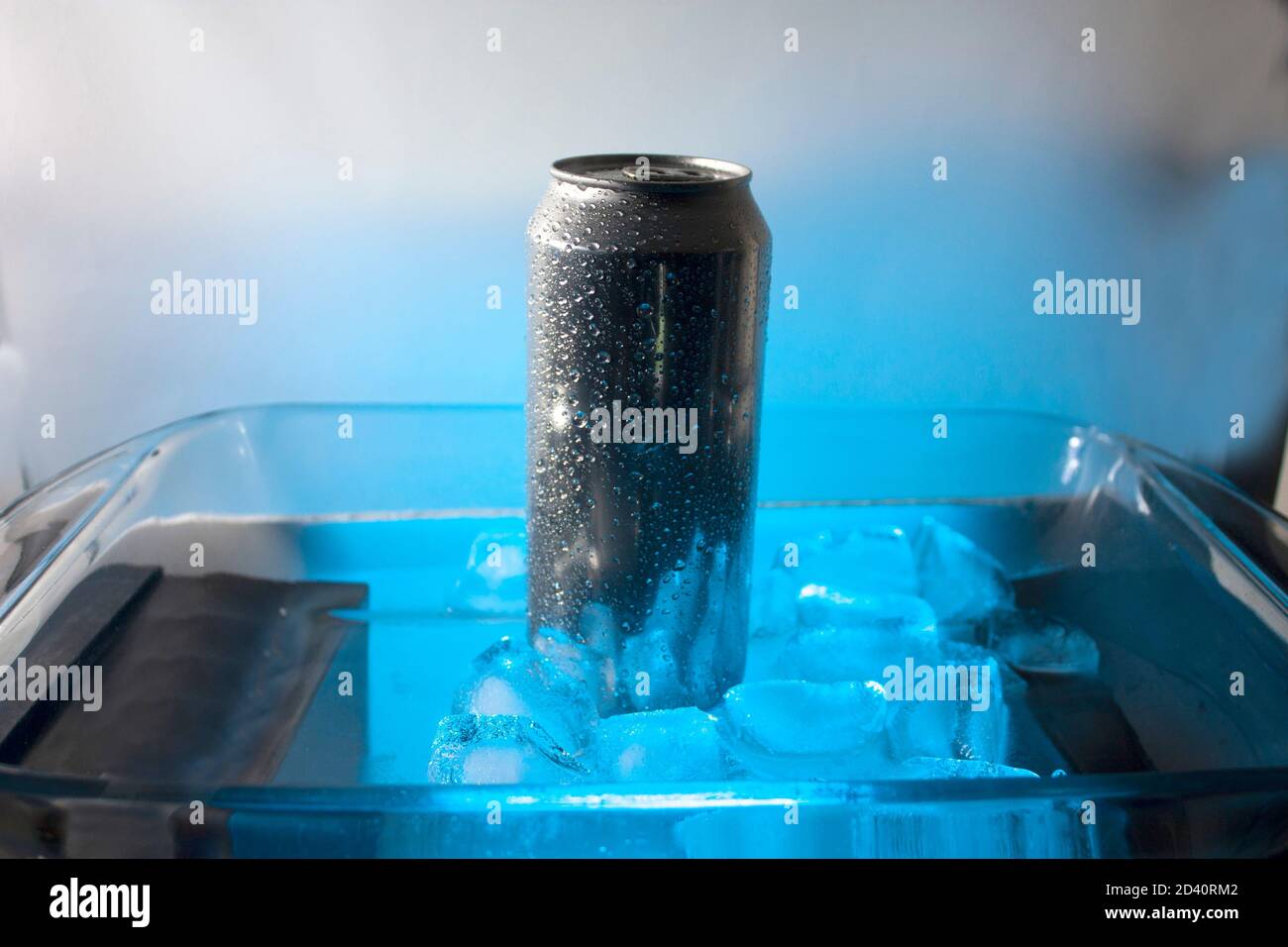 Silver can surrounded by icy drops and blue ice placed upright inside a ...