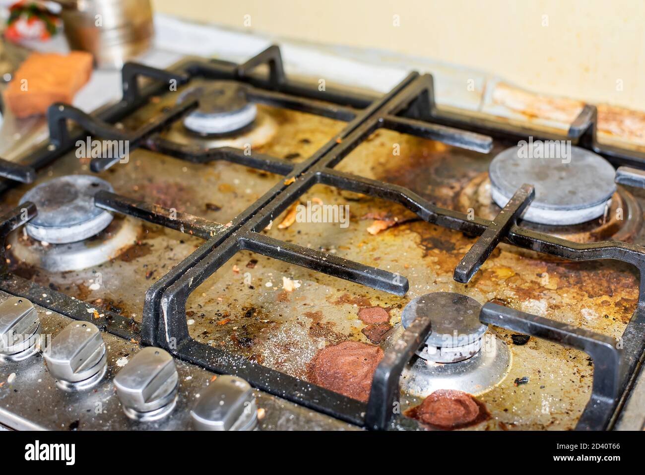 A scruffy and dirty kitchen, a stove in grease, in the sink a mountain ...