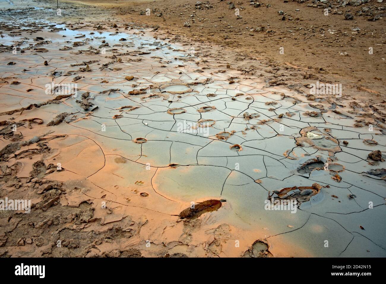 Smooth orange and blue cracked mud shines in the light only broken by ...