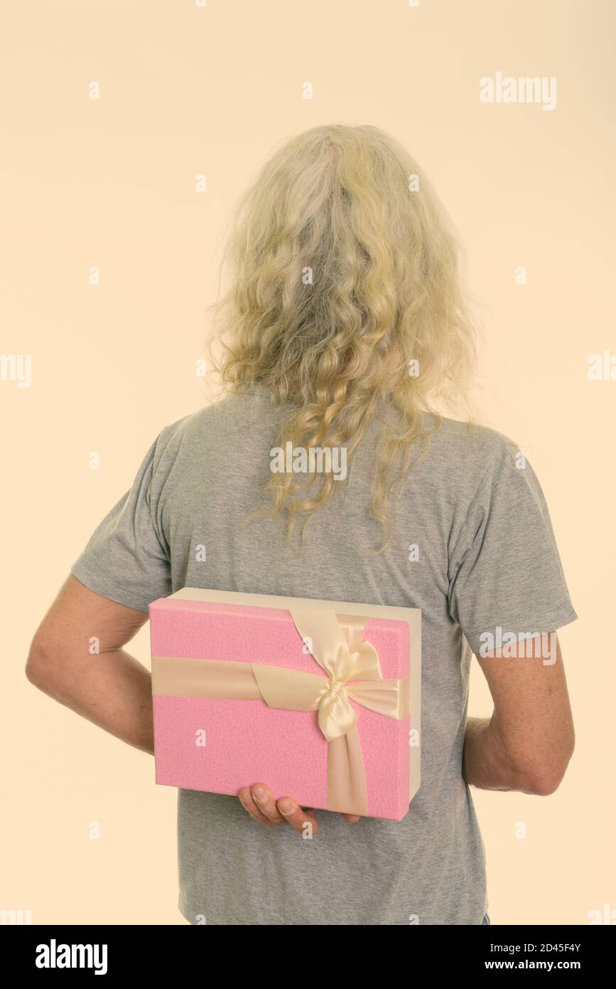 Back view of senior bearded man hiding gift box behind back ready for ...