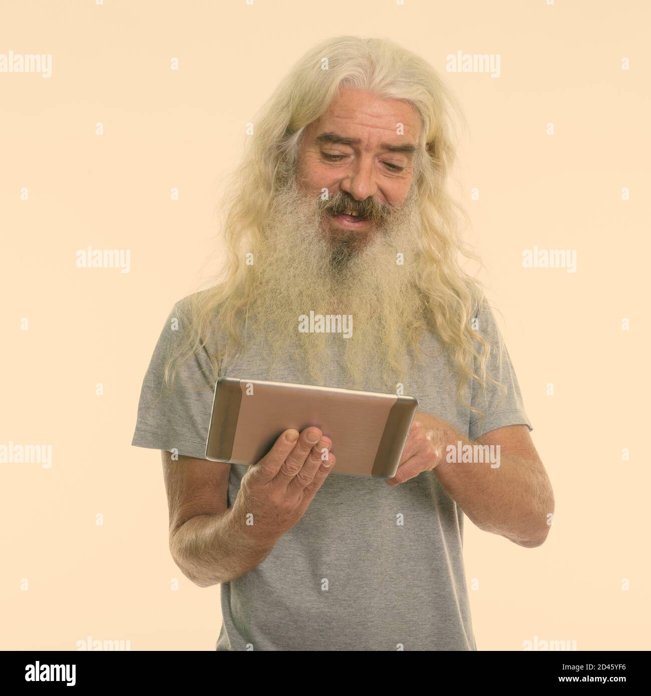 Studio shot of happy senior bearded man smiling while using digital ... Studio shot of happy senior bearded man smiling while using digital ...