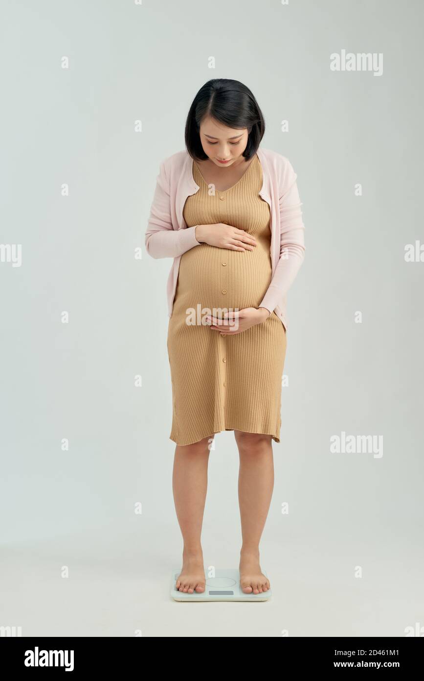Pregnant woman standing on scales at home. Pregnancy weight gain ...