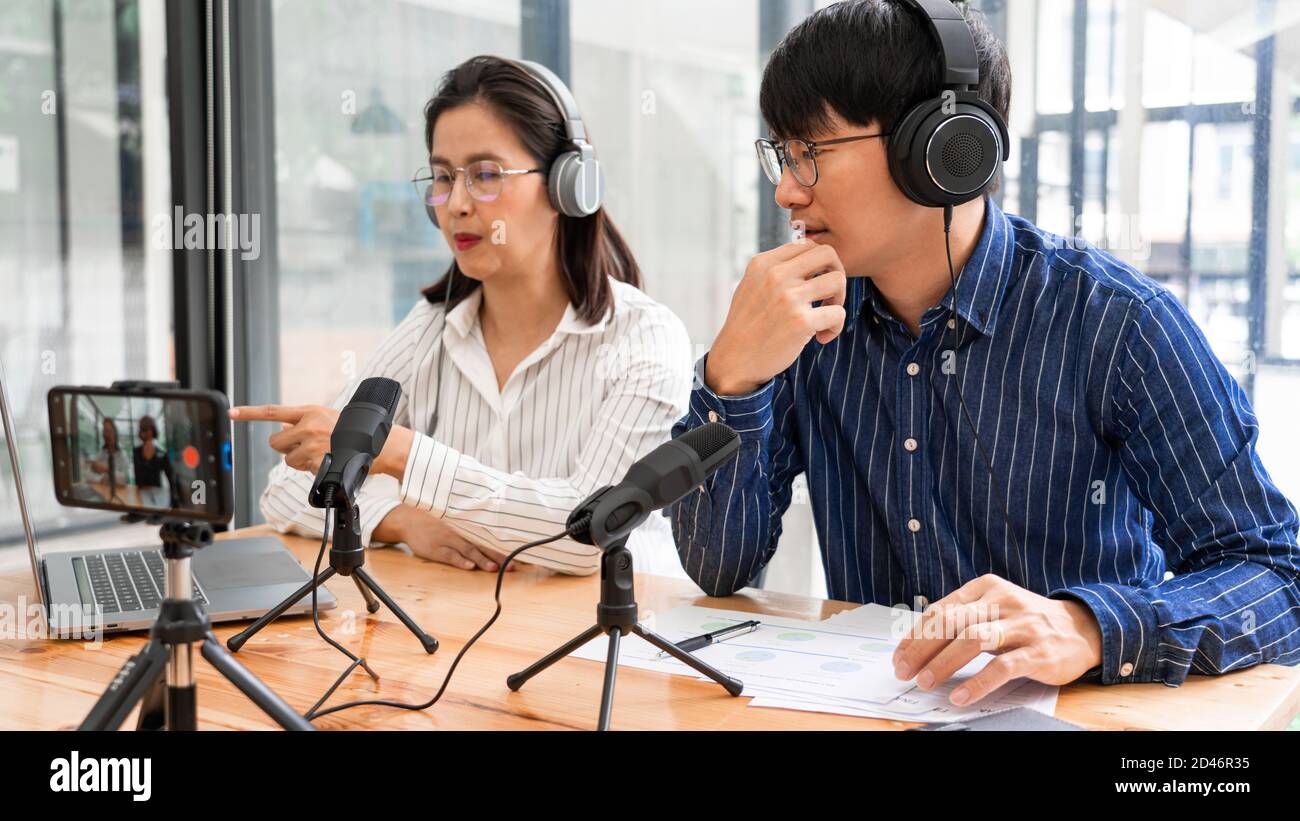 Asian Man and woman podcasters in headphones recording content with ...