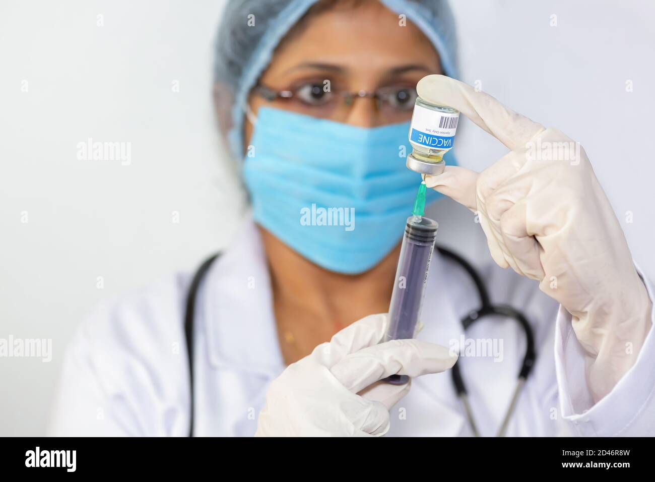 Indian doctor draw medication into an injection syringe from a vaccine ...
