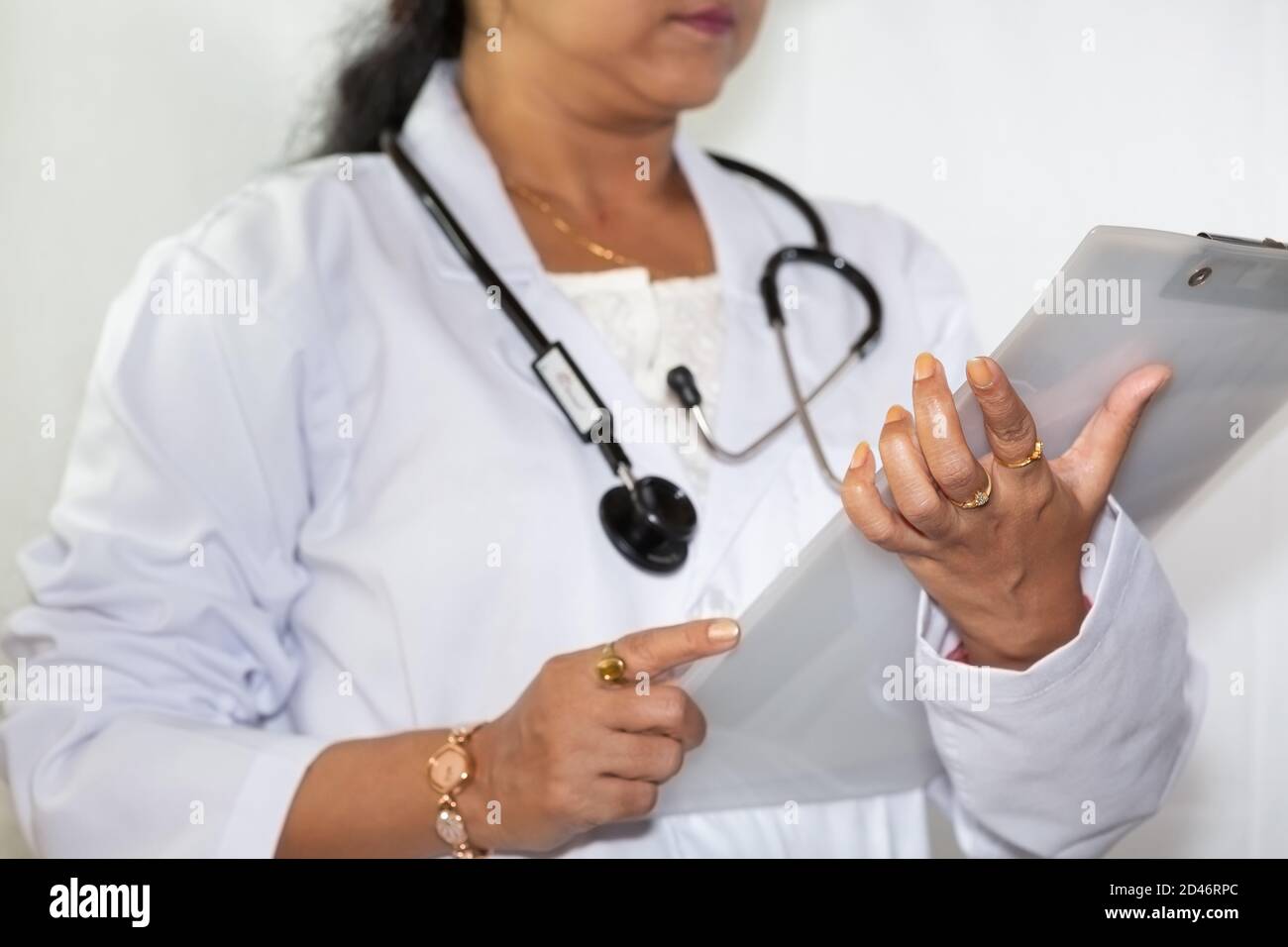 Indian female doctor wearing a stethoscope examine a medical report at ...